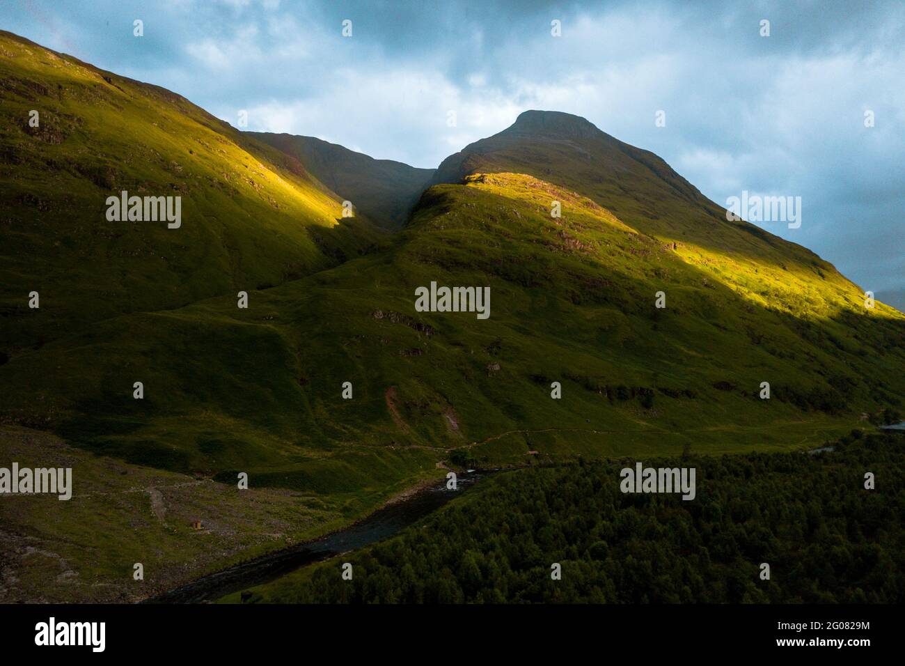 Overcast sundown sky over hill slope and curvy river in peaceful ...