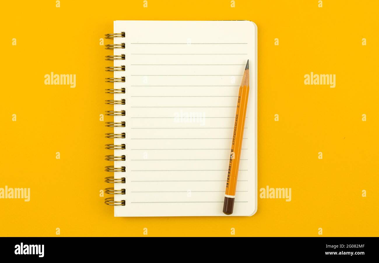 Notepad with pencil on a bright colorful orange table and background ...
