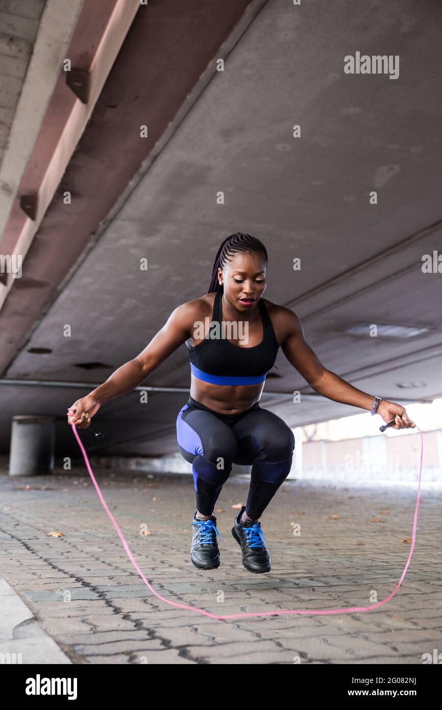 African American Woman in sportswear holding jump rope and looking at ...