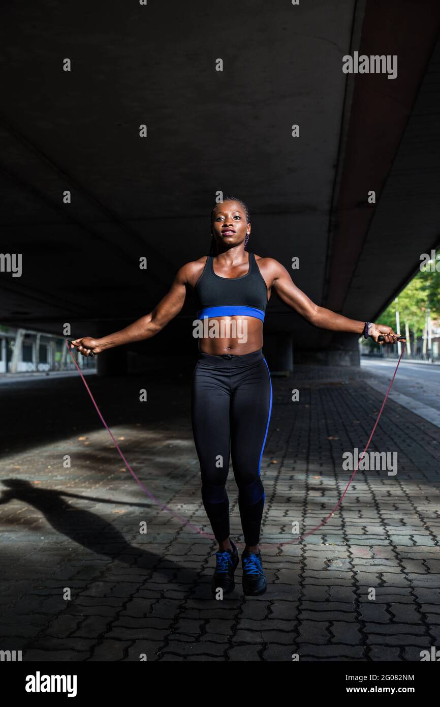 African American Woman in sportswear holding jump rope and looking at ...