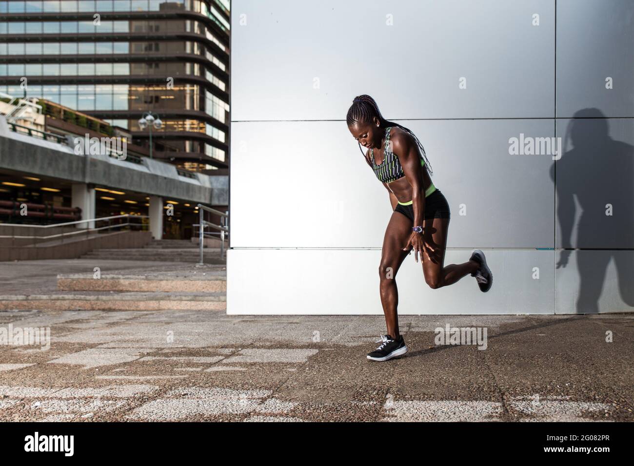 Side view of African American female athlete leaping forward while ...