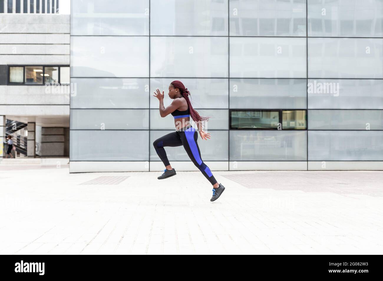 Side view of muscular African-American Woman sprinting at modern ...