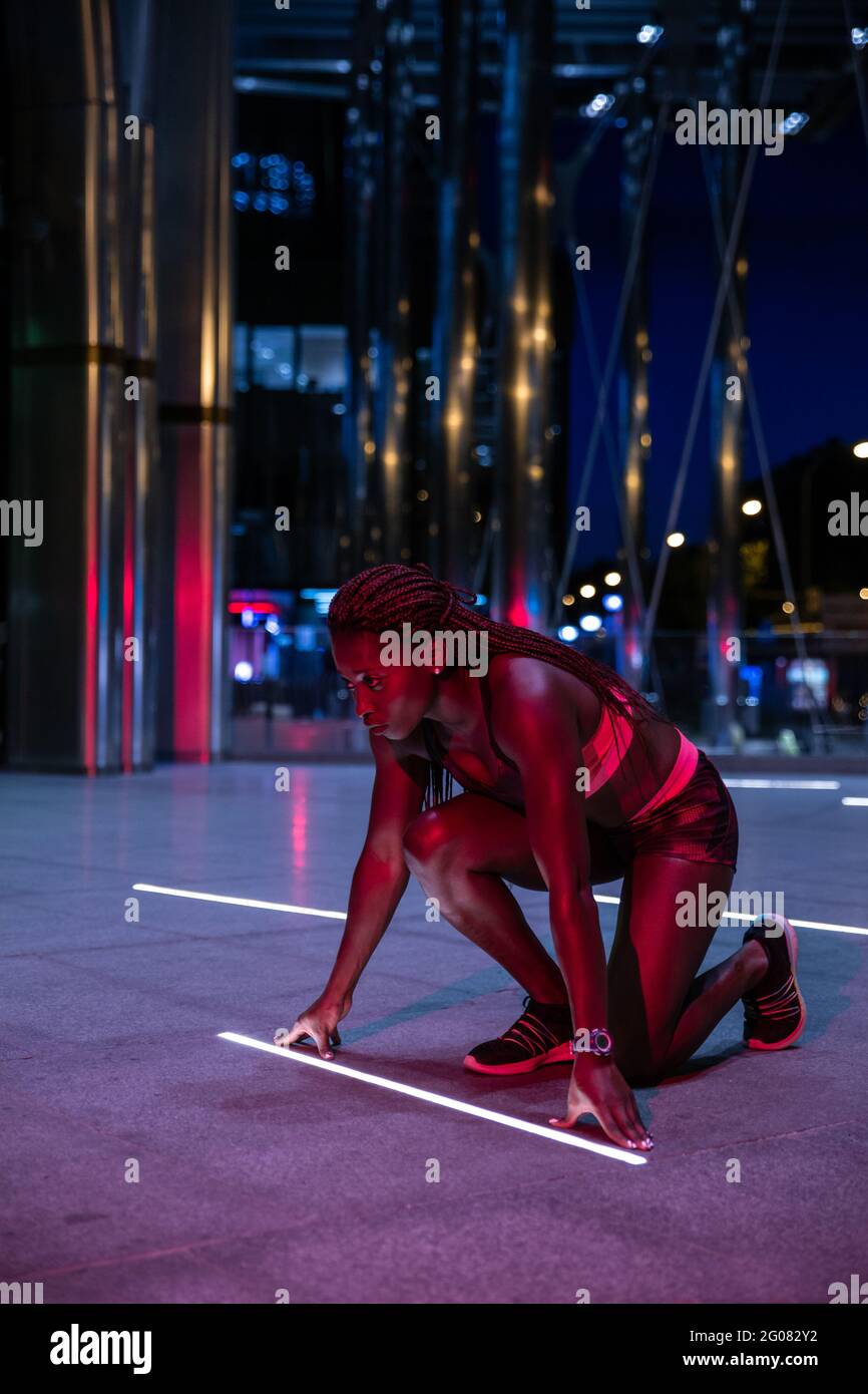 Side view of ethnic athletic Woman on crouch start prepared for sprint ...