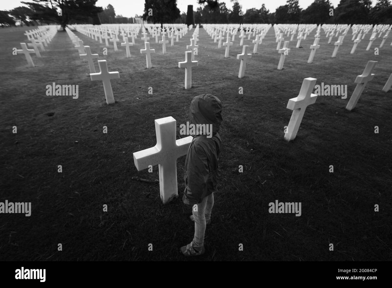 From above child contemplating a cross from a graveyard full of crosses ...