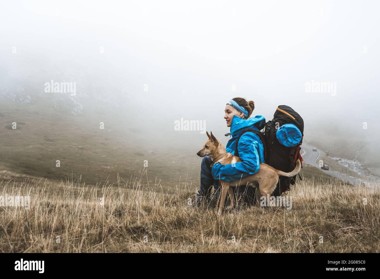 Side view of relaxed traveler in bright blue jacket with backpack ...