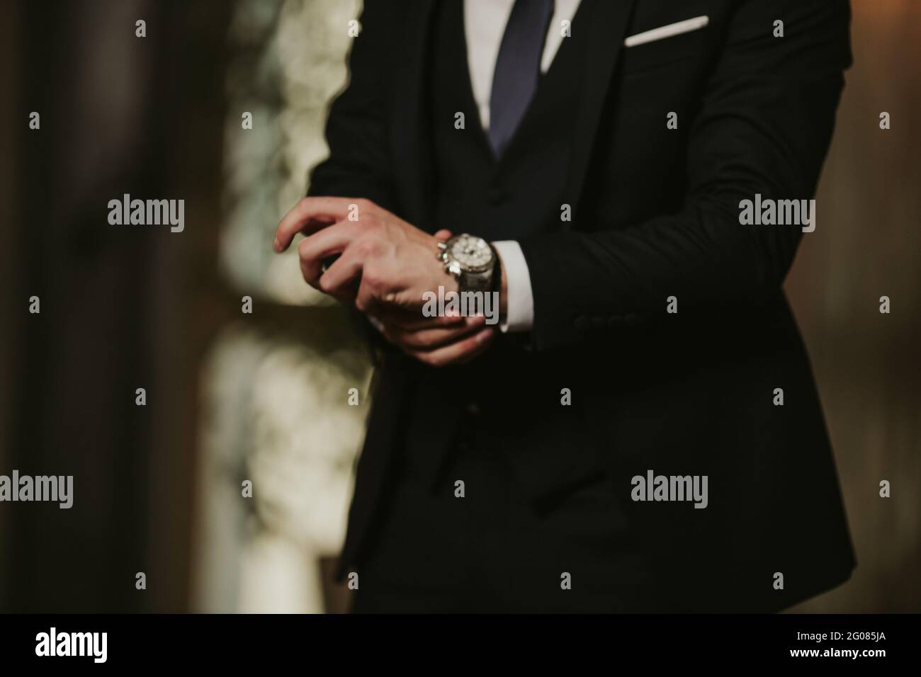 Closeup shot of a man in a black suit fixing his watch Stock Photo - Alamy
