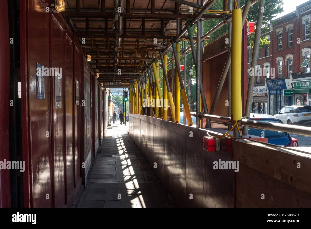 A footpath in Hanwell is enclosed by scaffolding and boarding to ...