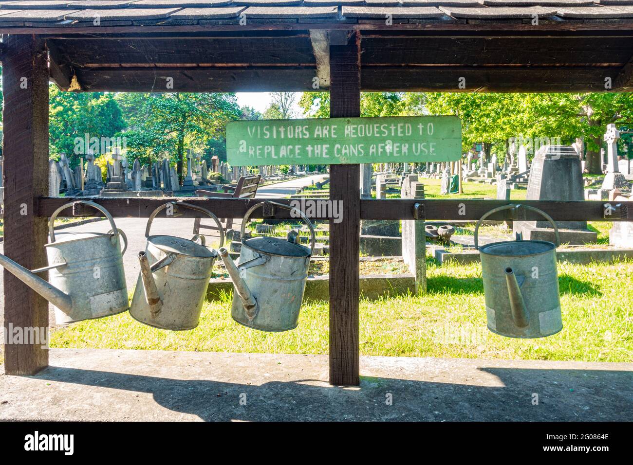 Metal watering cans hang on a rack in Hanwell Cemetery for visitors to ...