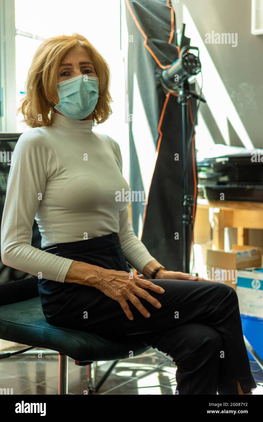 Vertical shot of a caucasian female in a face mask waiting sitting on a ...