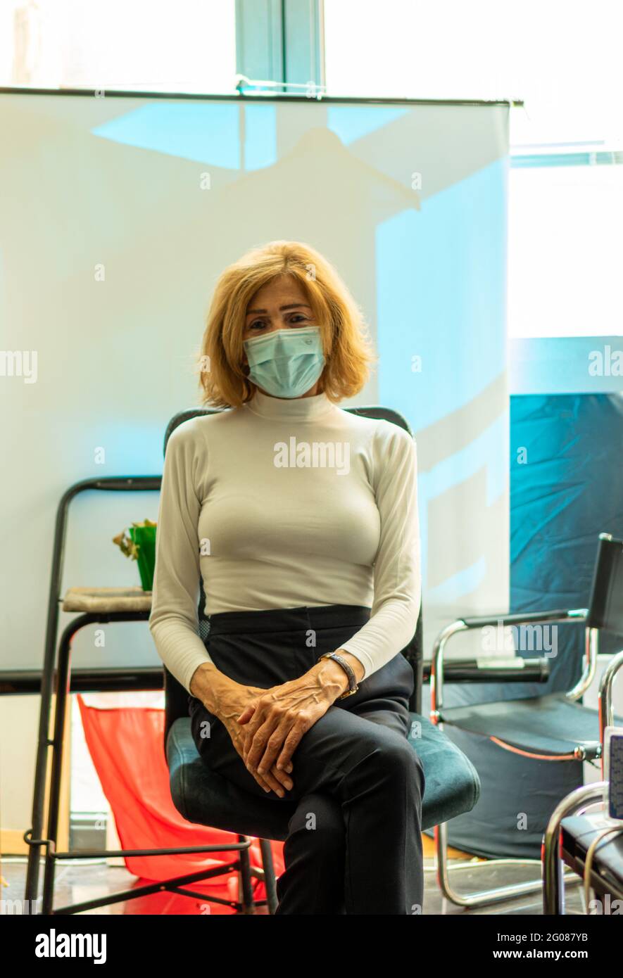 Vertical shot of a caucasian female in a face mask waiting sitting on a ...