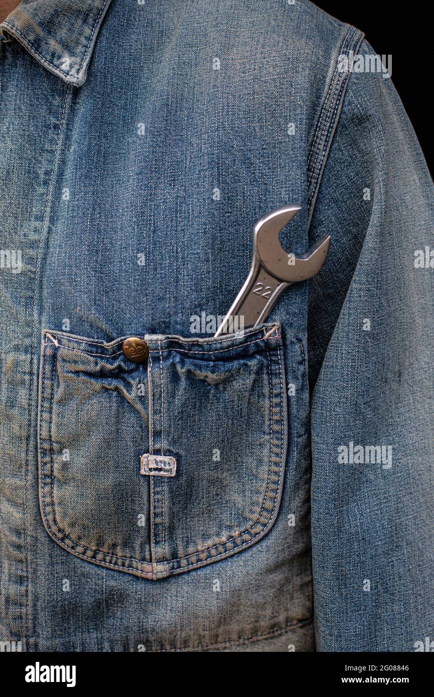 close up of spanner tool in denim work jacket pocket. spanner in jeans ...