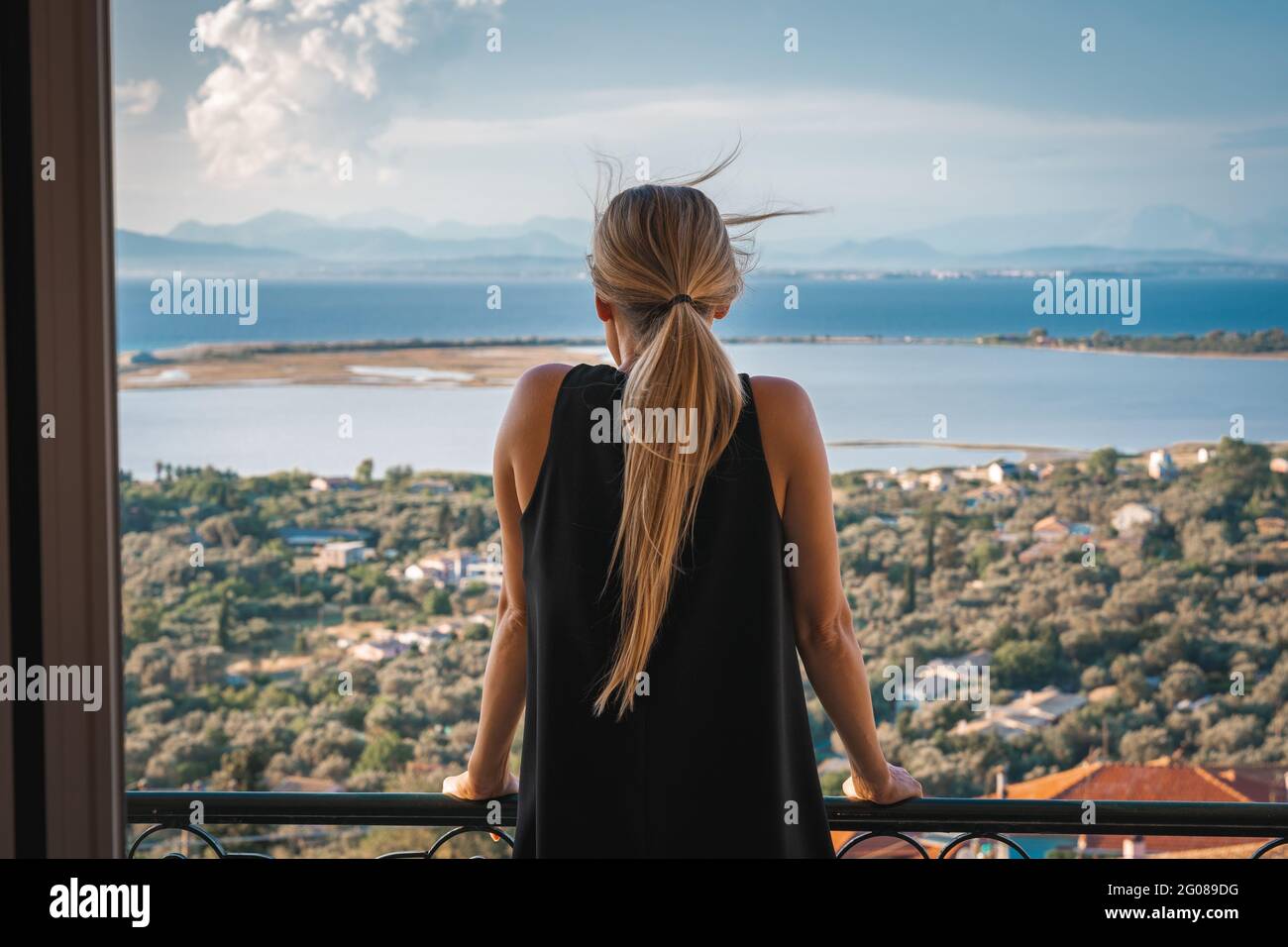Young woman enjoys seaside viewpoint from balcony Stock Photo - Alamy