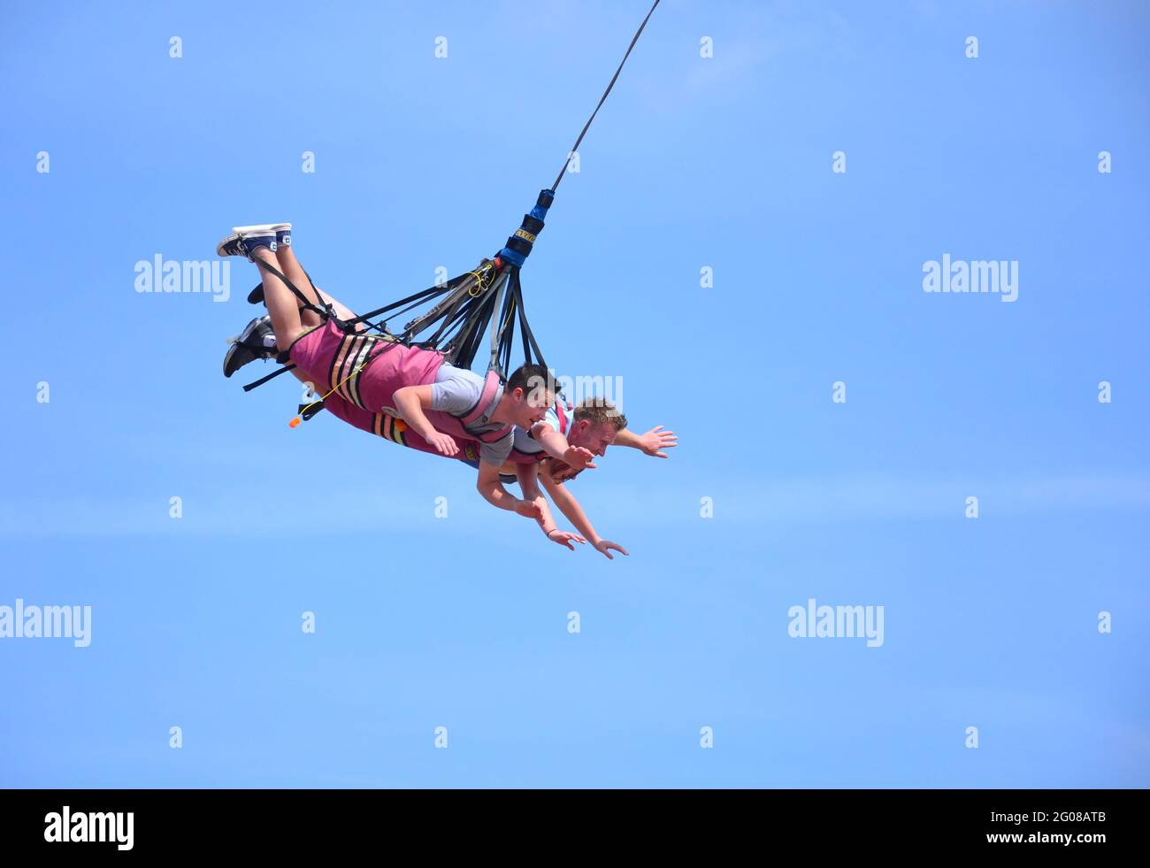 Two young men and a young woman, attached to a rope, fly through the ...