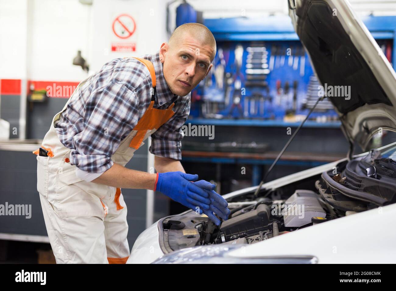 Positive man car mechanician repairing car in auto repair service Stock ...