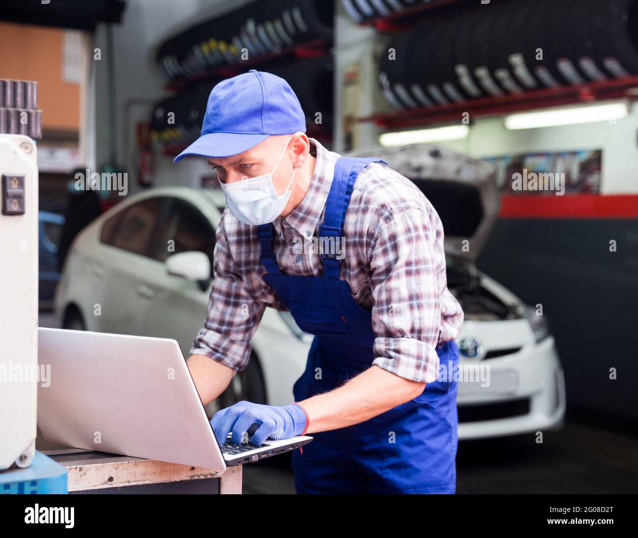 Auto mechanic in face mask using a laptop computer checking car Stock ...