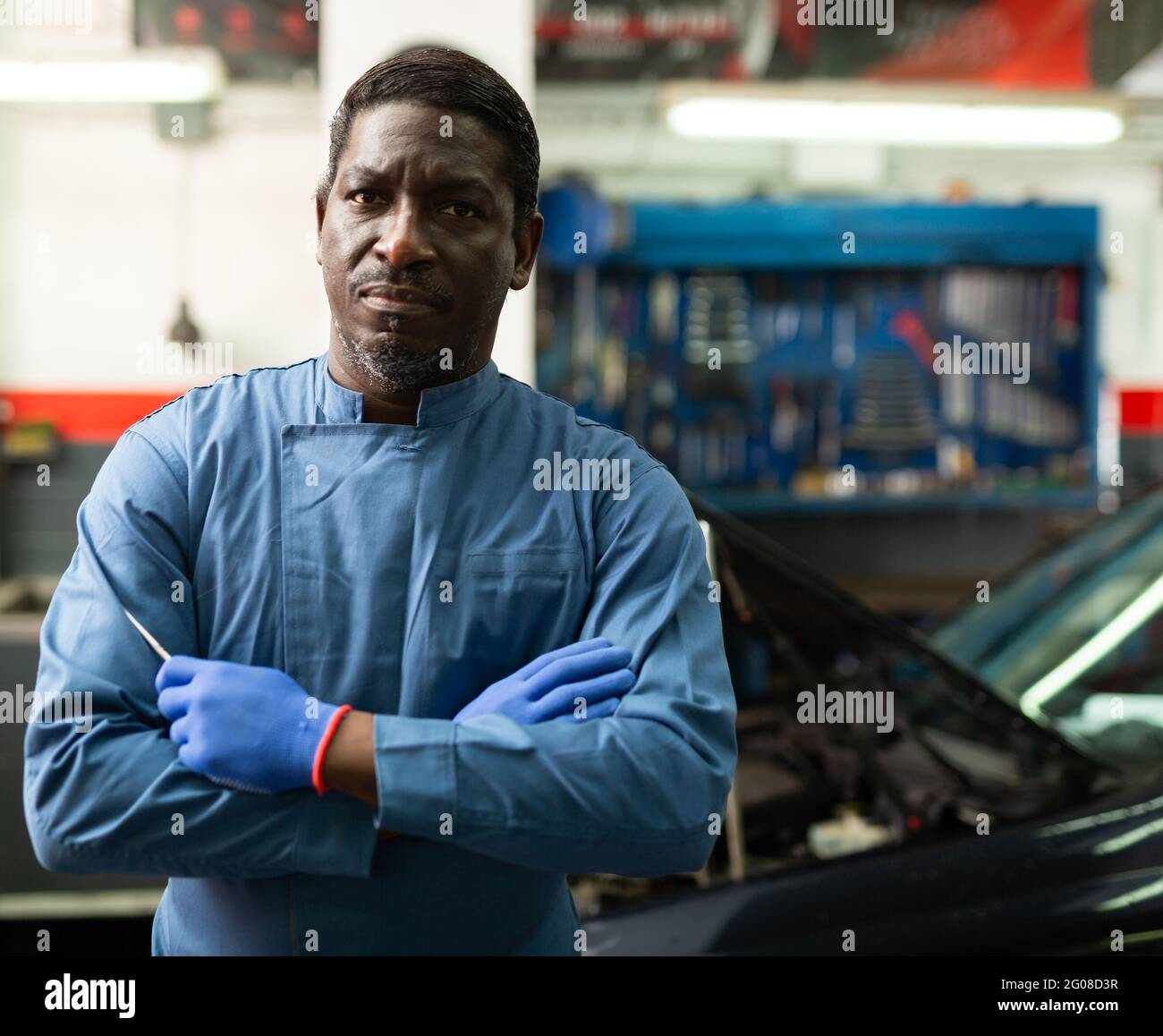 Professional man car mechanician standing near repairable car in auto ...