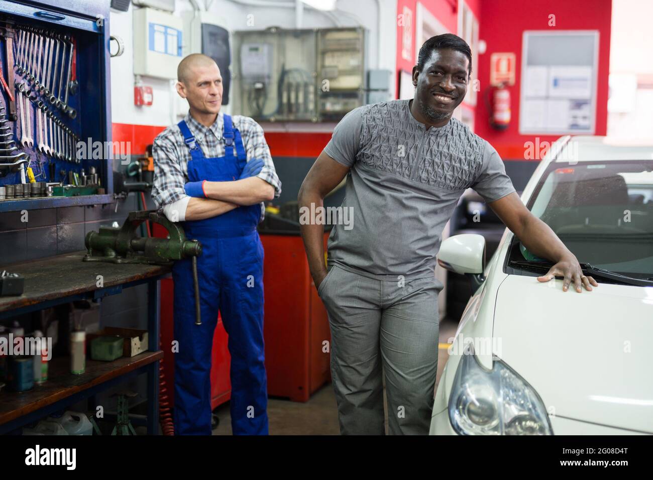 Happy man client with mechanic standing near repaired car Stock Photo ...