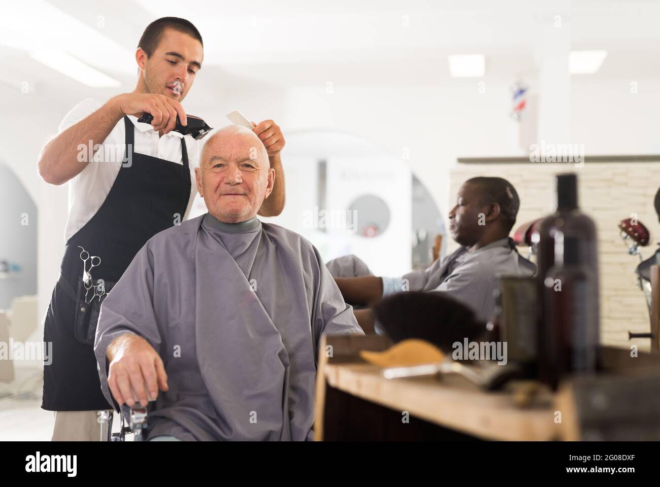 Stylist performing haircut of gray-haired man Stock Photo - Alamy