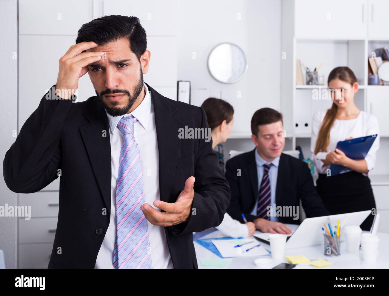 Tired man at office with working colleagues Stock Photo - Alamy
