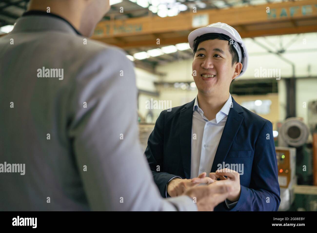 30s young Asian businessman in formal suit and hard hat showing foreign ...