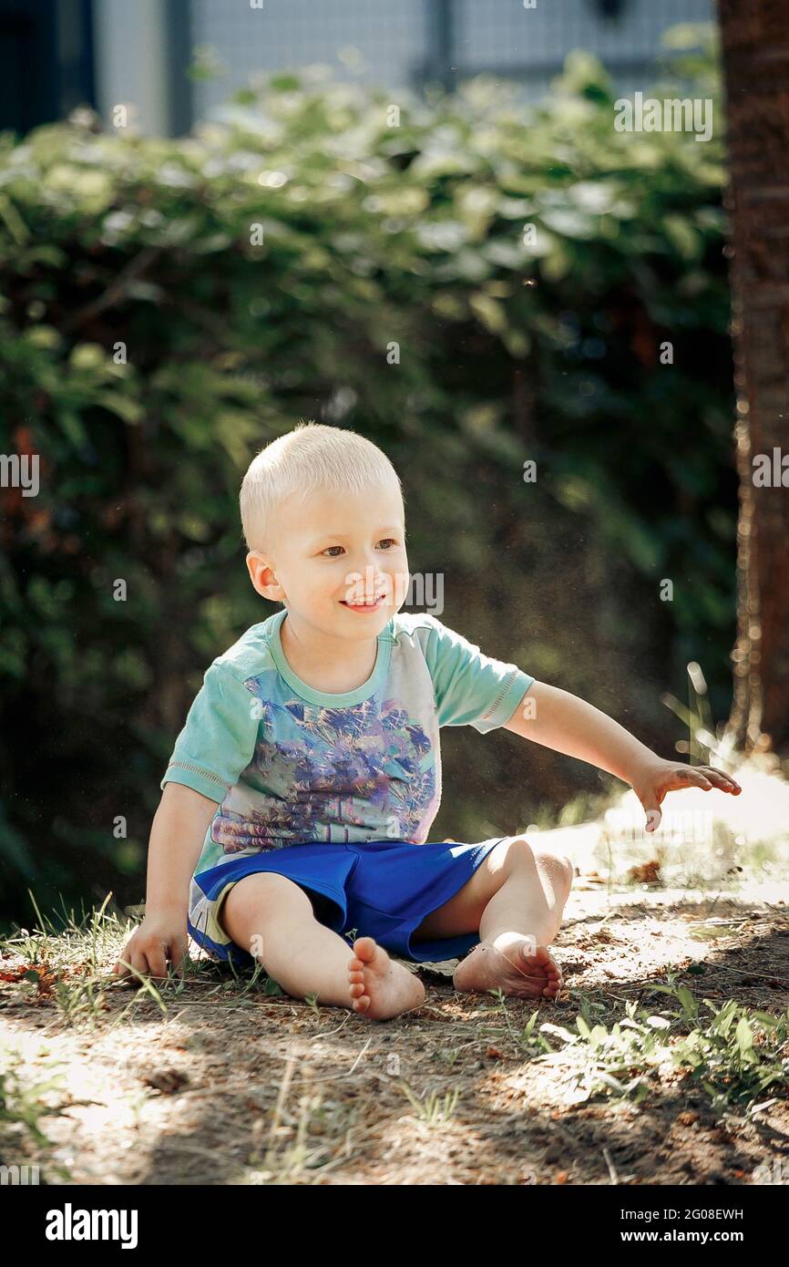 Barefoot boy sits on the sand Stock Photo - Alamy
