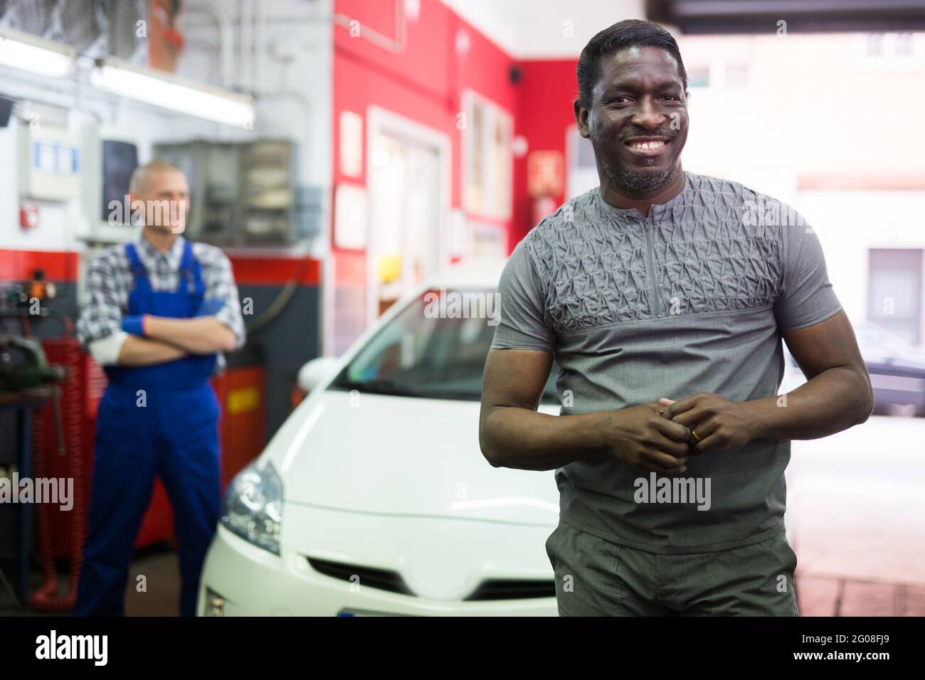 Happy man client with mechanic standing near repaired car Stock Photo ...