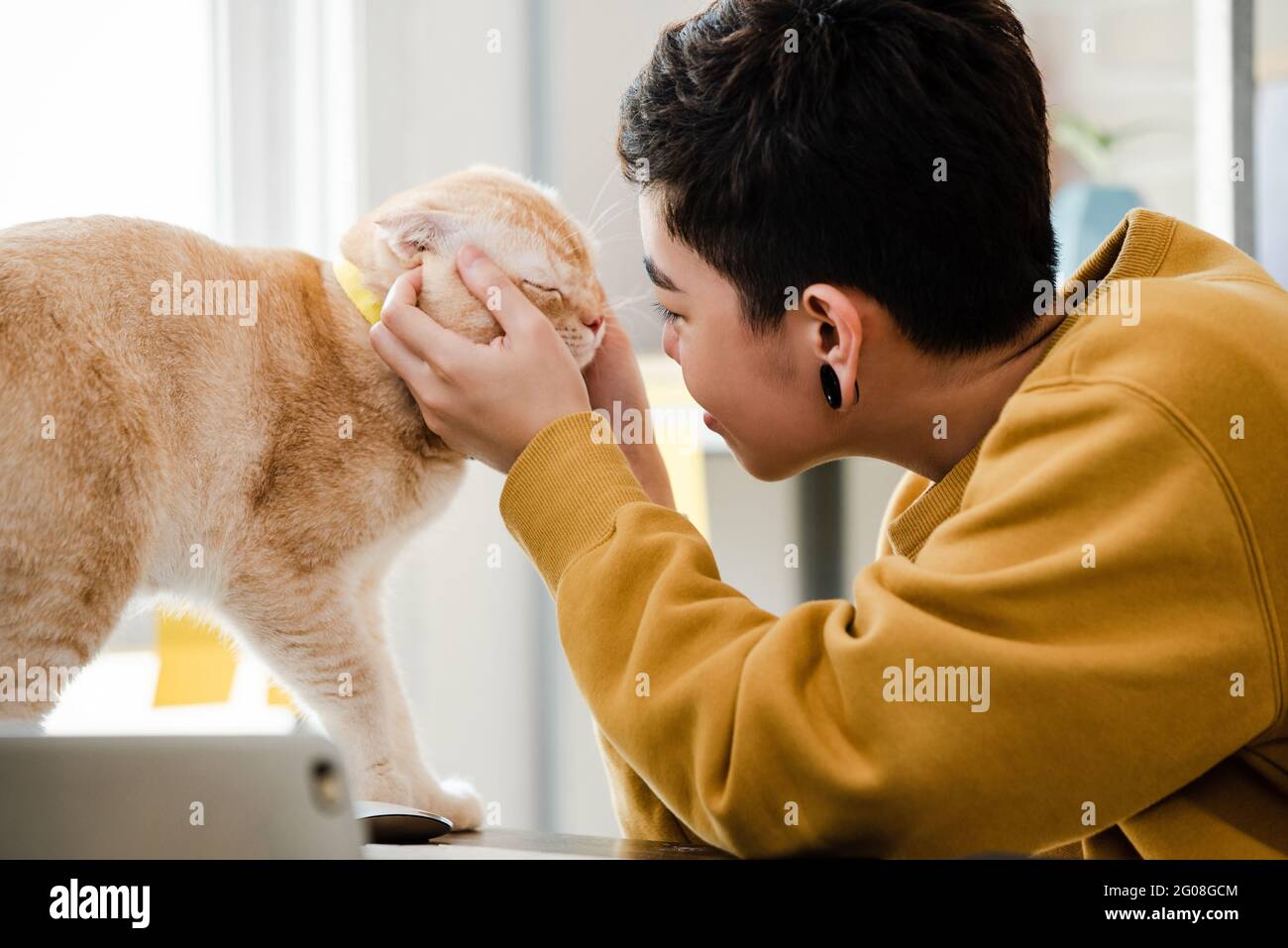 Young Asian female happily touching and looking at her cat Stock Photo ...