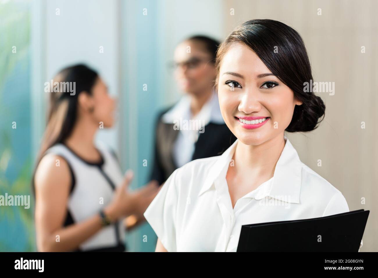 Chinese Business woman standing in front of team Stock Photo - Alamy