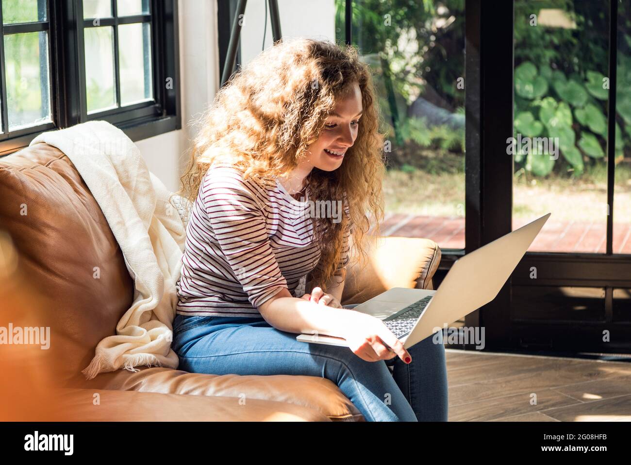 Pretty smiling Caucasian woman using laptop computer on the couch at ...