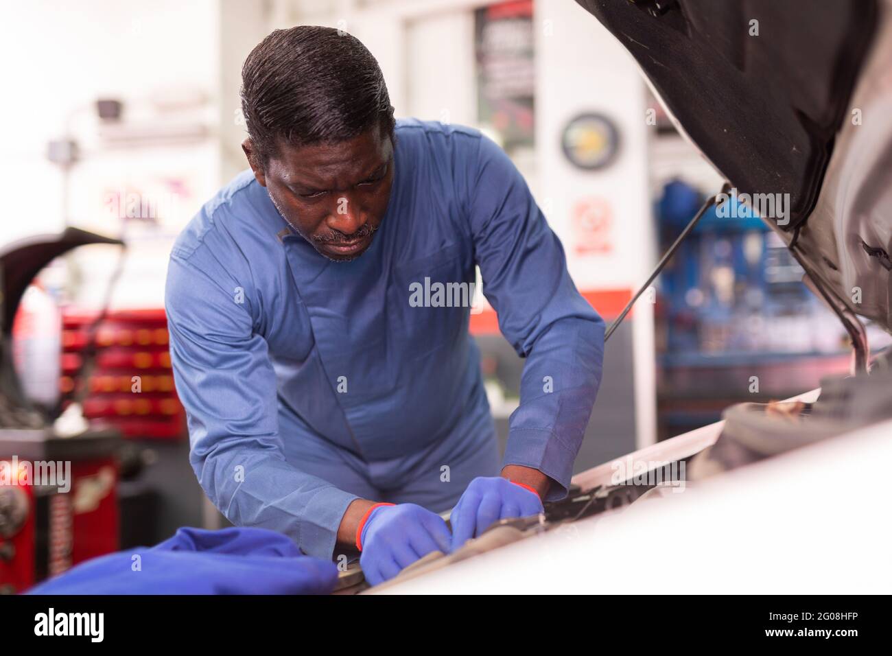 Professional american mechanic man in uniform repairing car engine ...