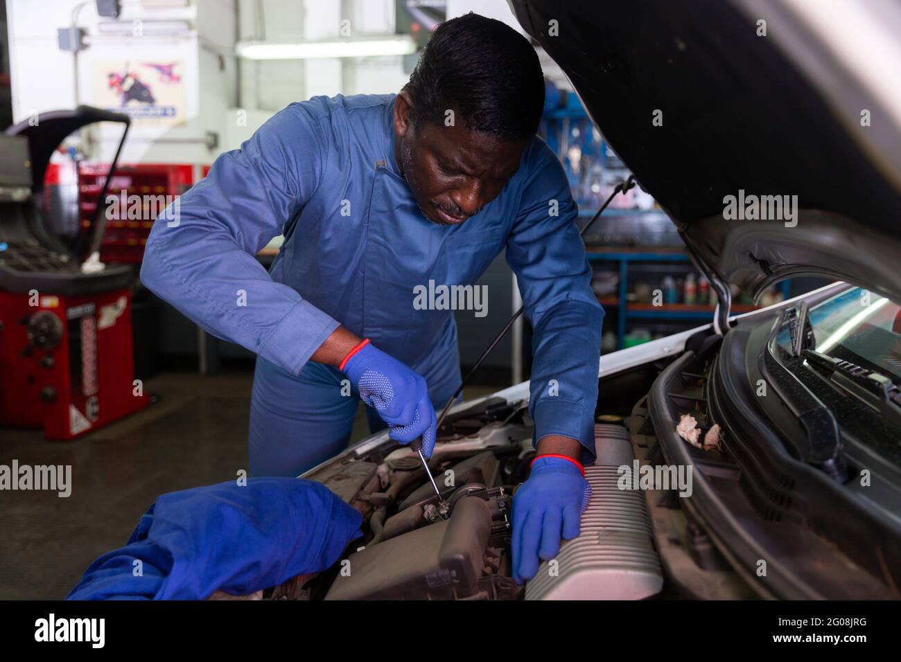 Professional american mechanic man in uniform repairing car engine ...