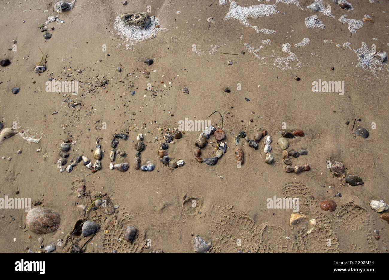 the word welcome written in the sand at the sea with pebble stone ...