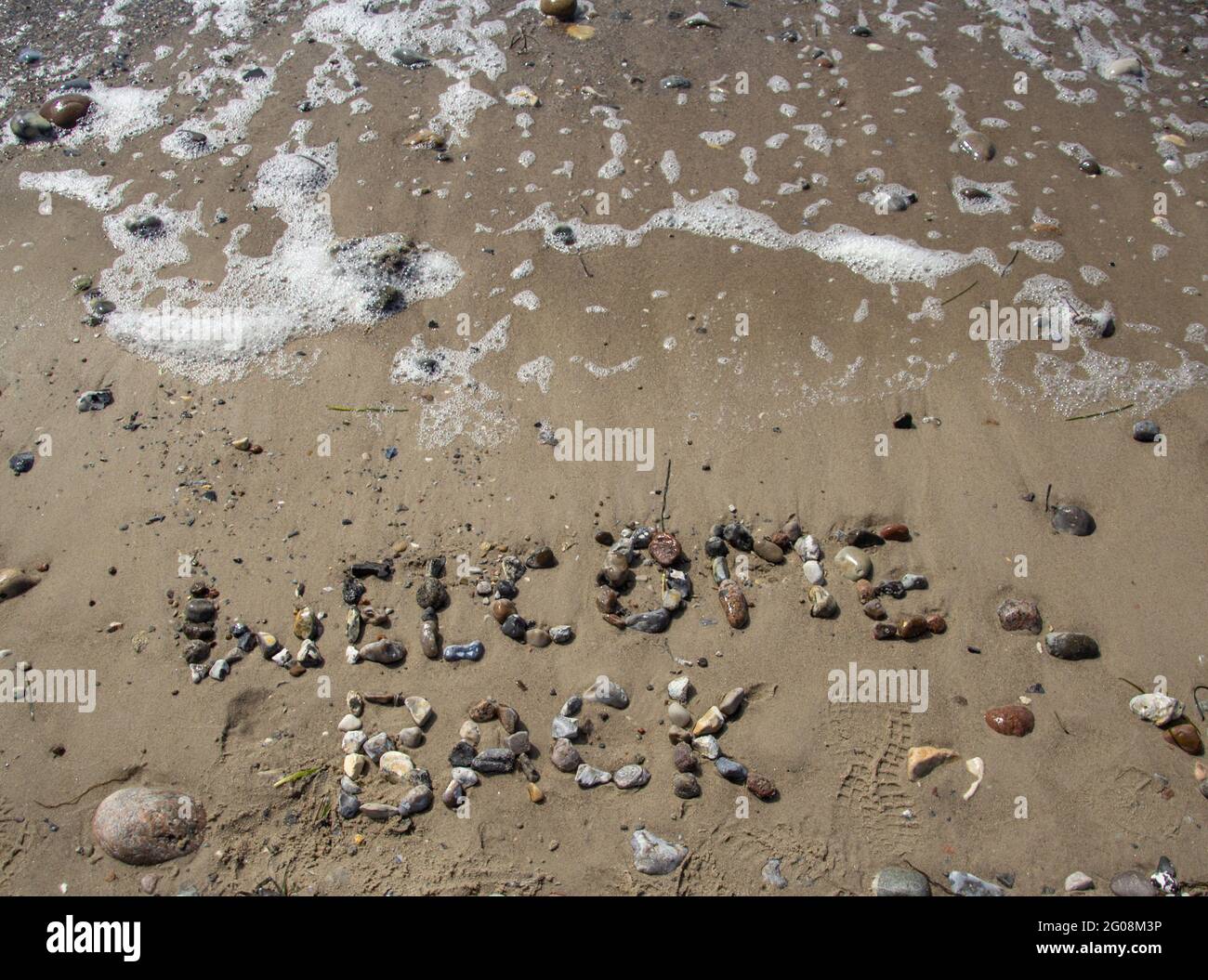the words welcome back written in the sand at the sea with pebble stone ...