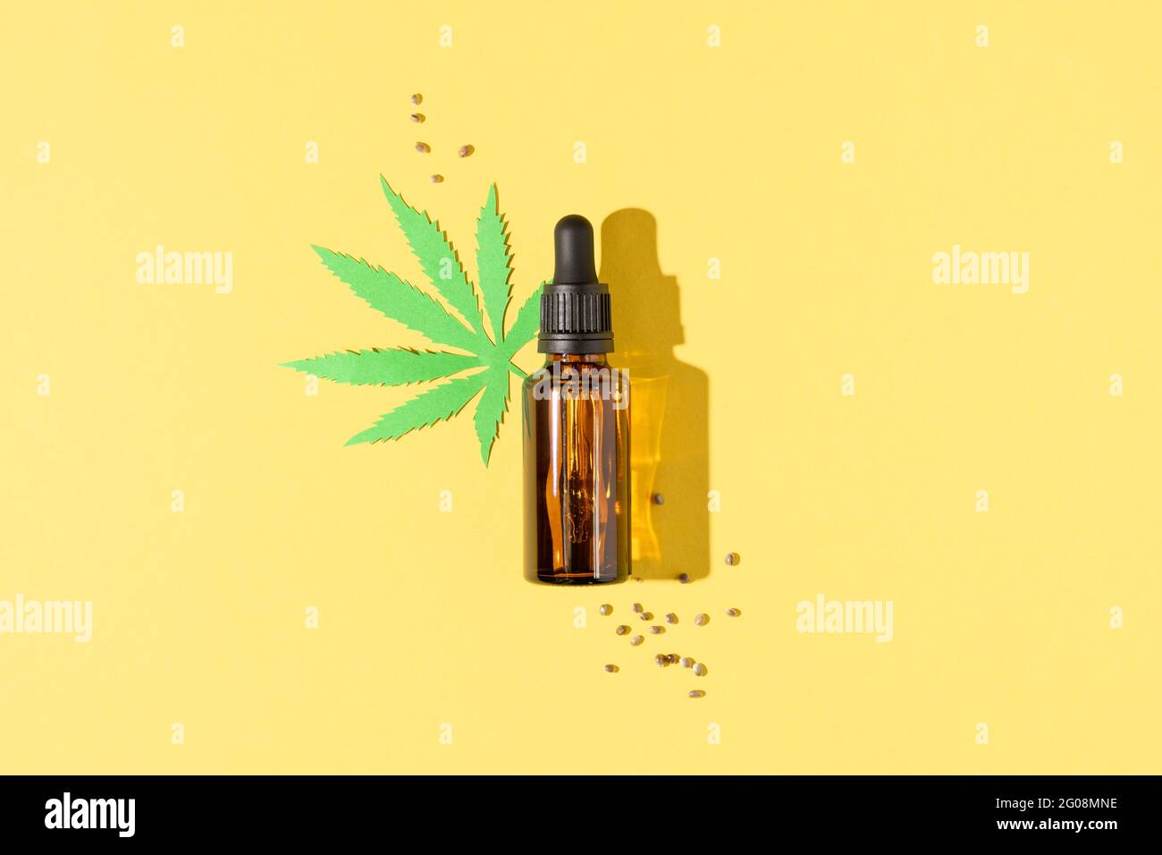 Cannabis oil extract in droplet bottle and seeds on yellow background ...