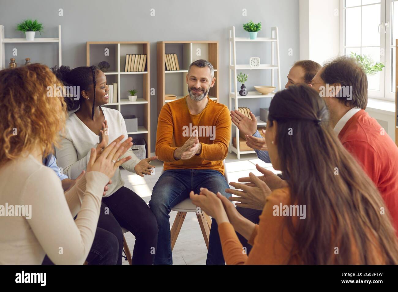 Happy patients applauding mature psychologist or therapist after group ...