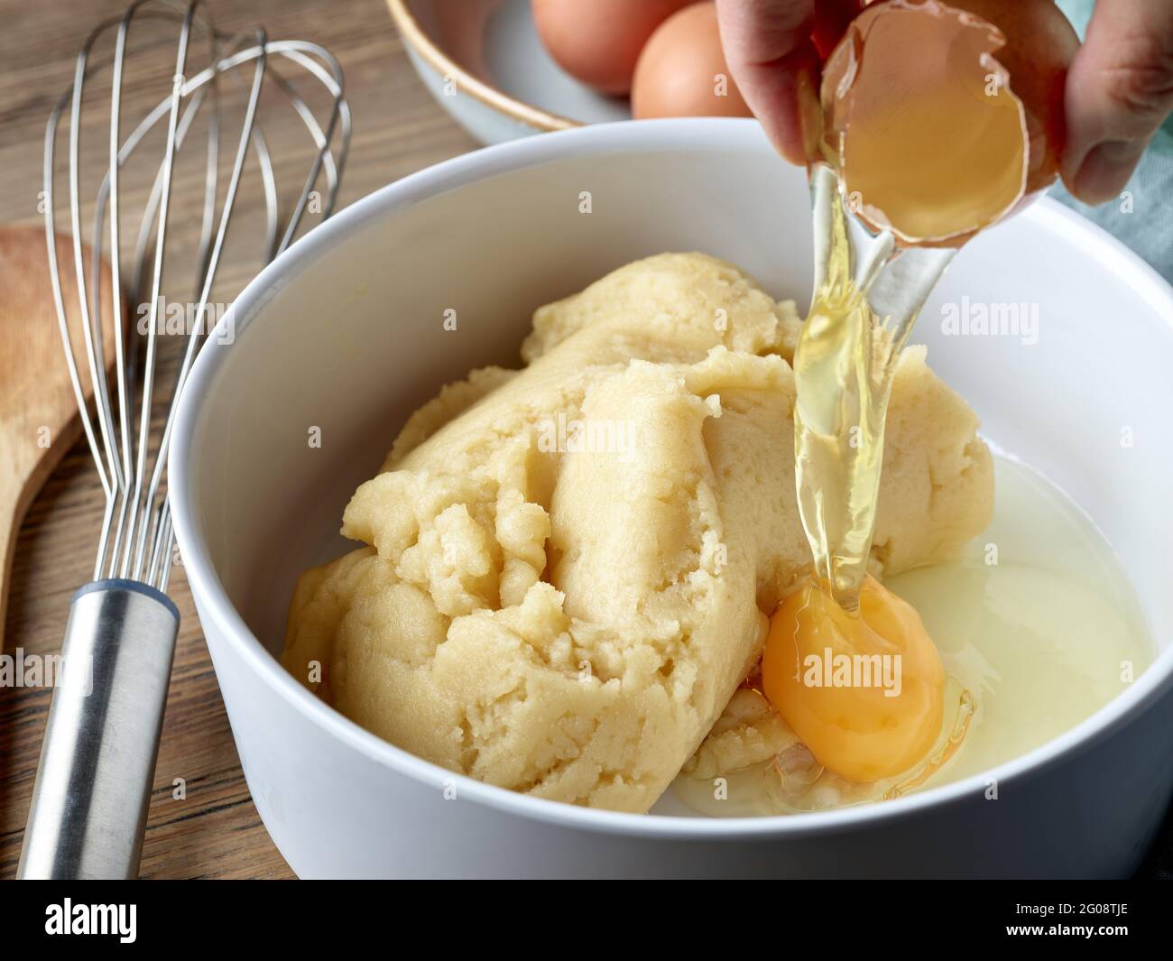 process of making custard dough for eclairs and cream puffs, egg is adding Stock Photo - Alamy