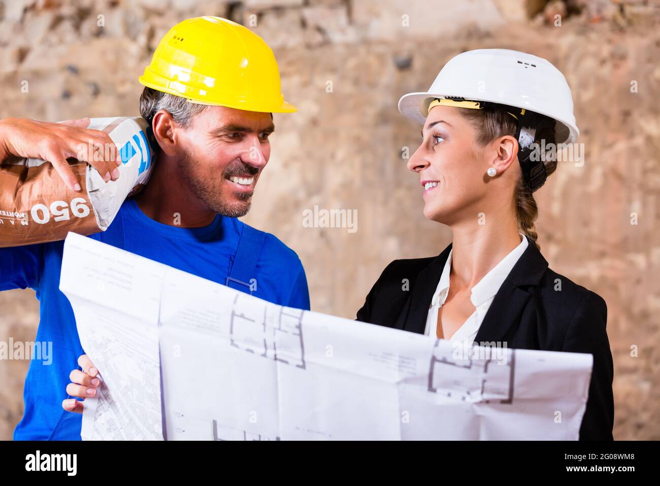 Architect and construction worker on site with plan or blueprint Stock ...