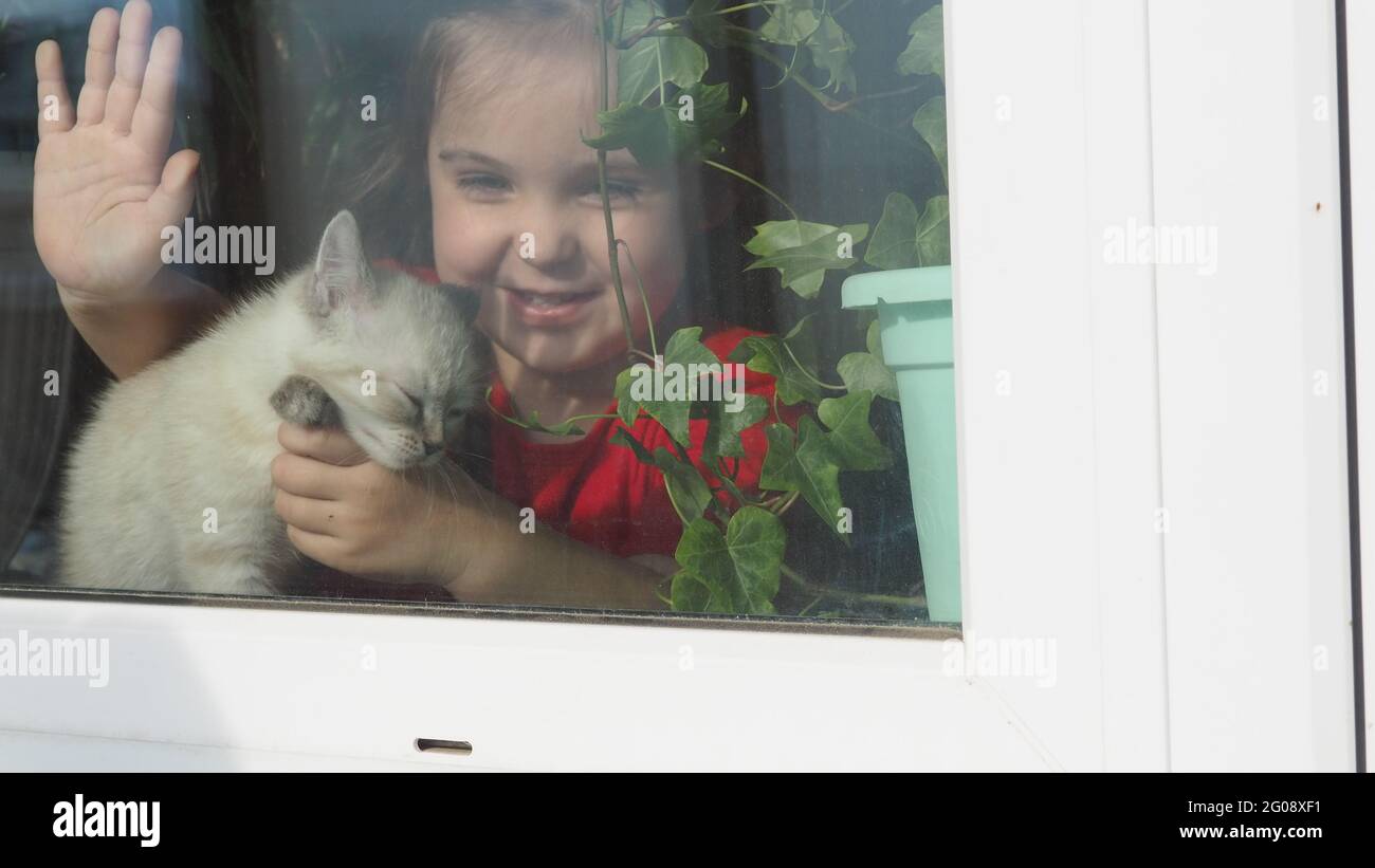 Beautiful little girl smiling and watching out the window. A child ...