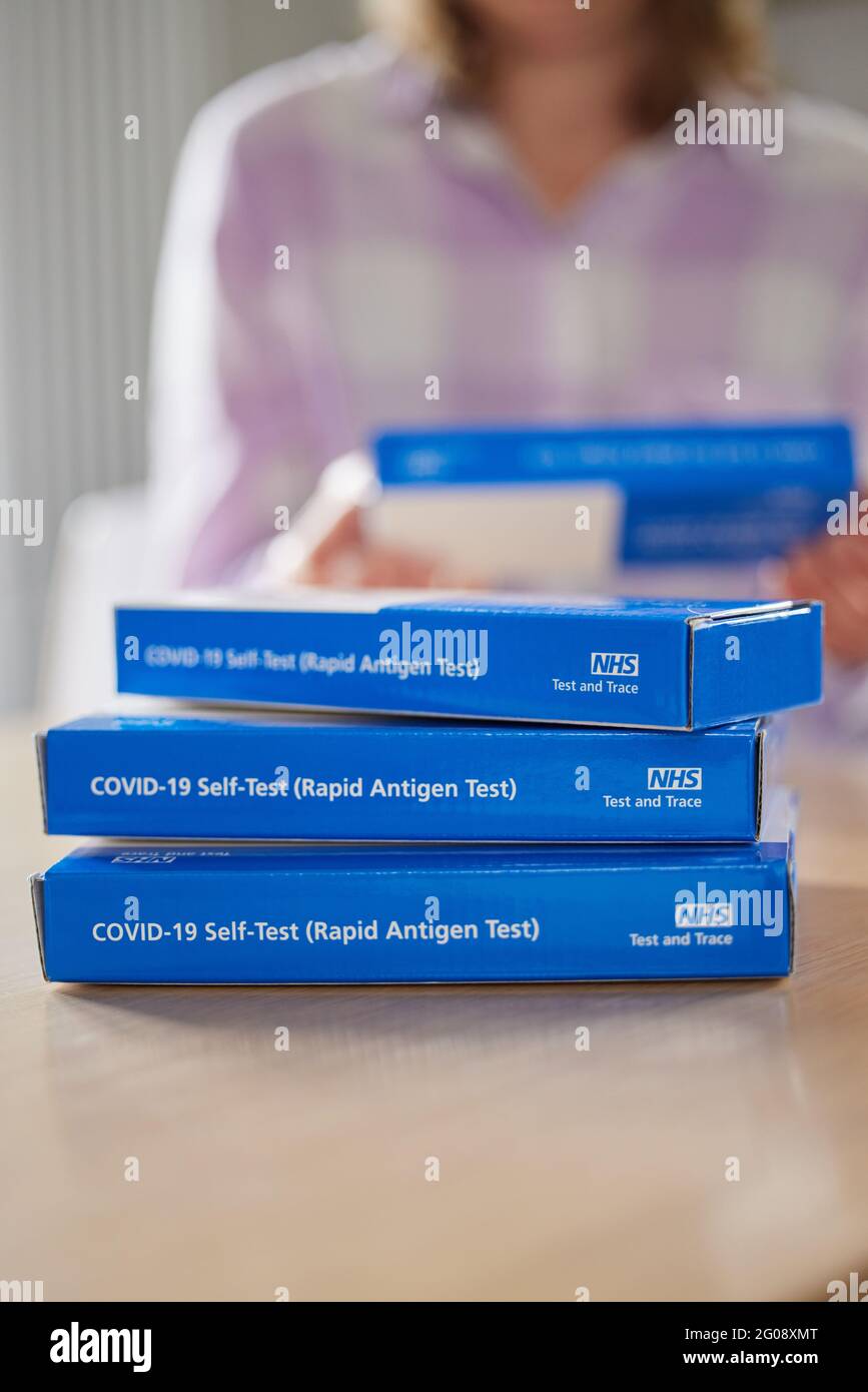 Close Up Of Woman At Home Reading Instructions On Supply Of NHS Covid ...