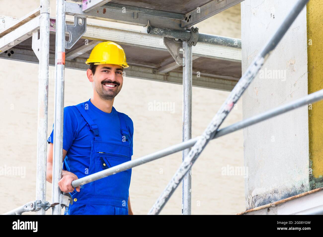 Builder on construction site at scaffold Stock Photo - Alamy