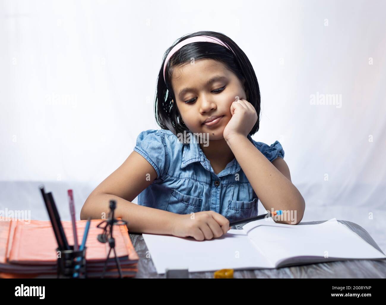 A pretty Indian girl child getting bored during study on white ...