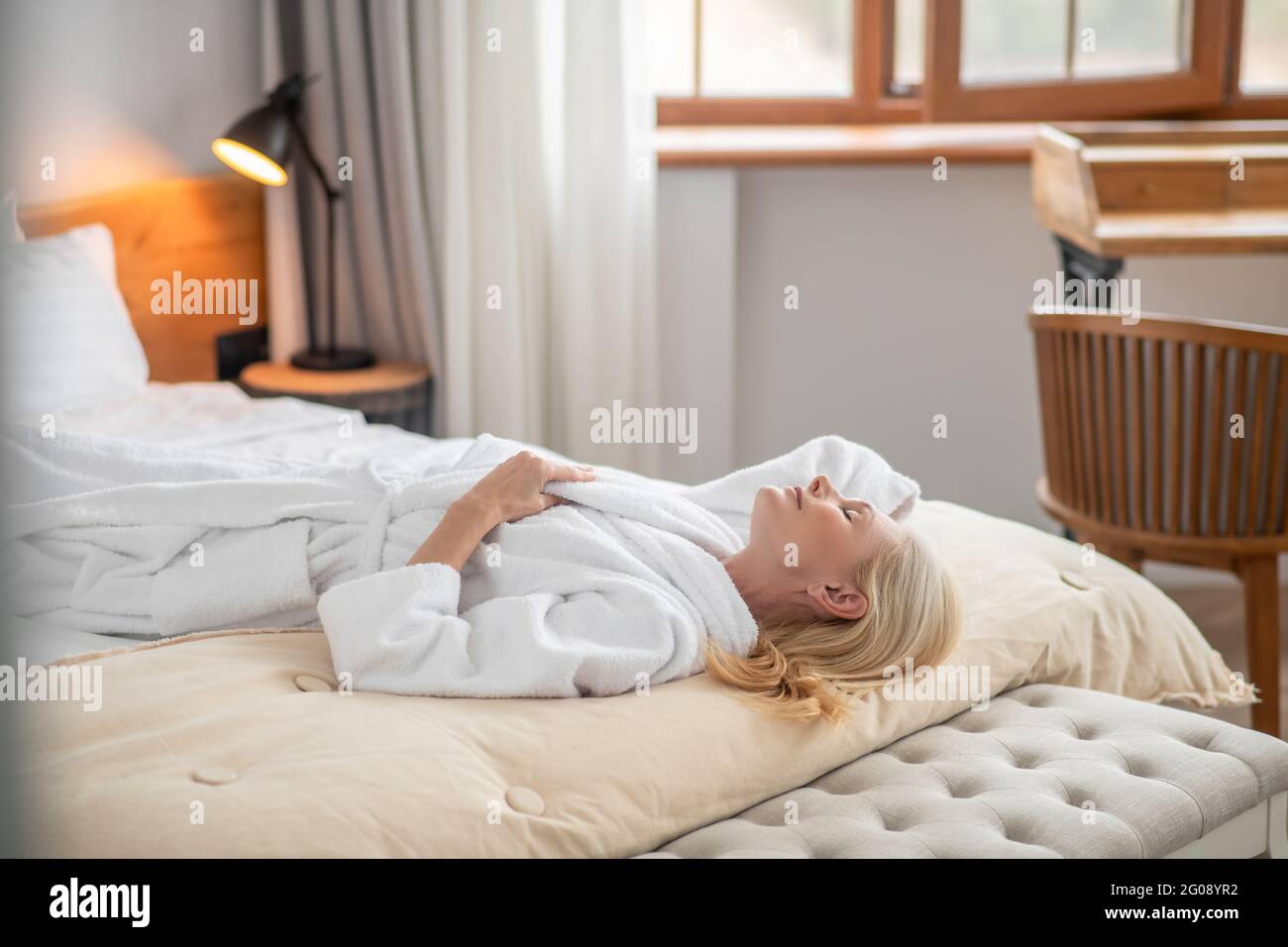 A beautiful woman in a white bath robe laying on a bed Stock Photo - Alamy