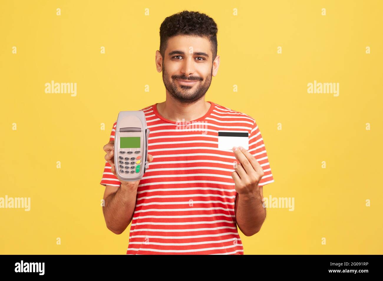 Smiling man with beard in striped t-shirt holding and showing pos ...