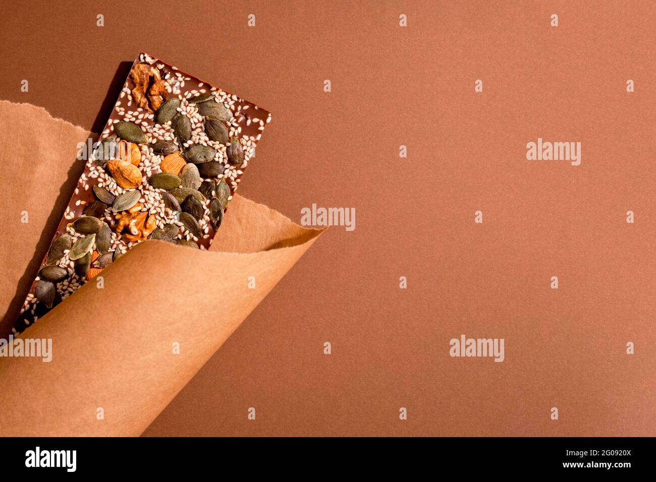 Top view on natural organic chocolate bar with nuts and seeds on brown ...
