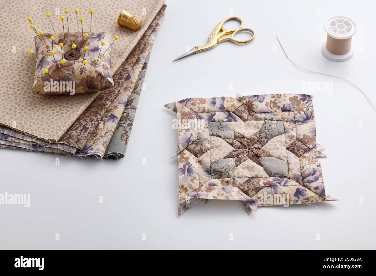 Patchwork block, a stack of fabrics, sewing and quilting accessories ...