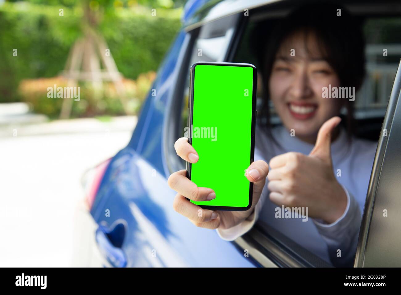 Asian woman driver sitting in the car and holding mobile phone with ...