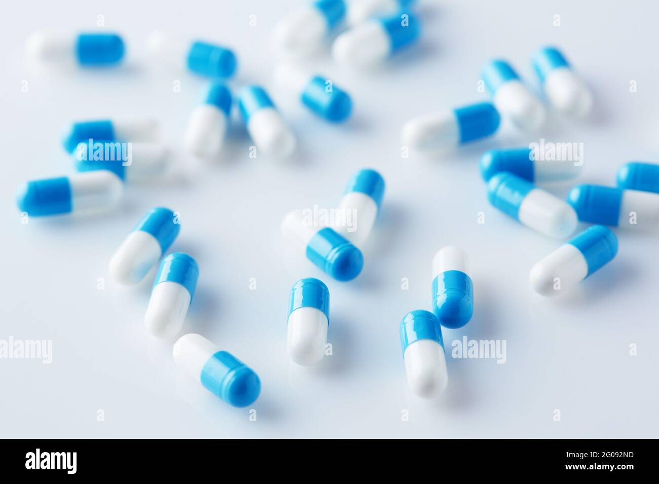 Blue and white capsules pill spread on white background with shadow ...