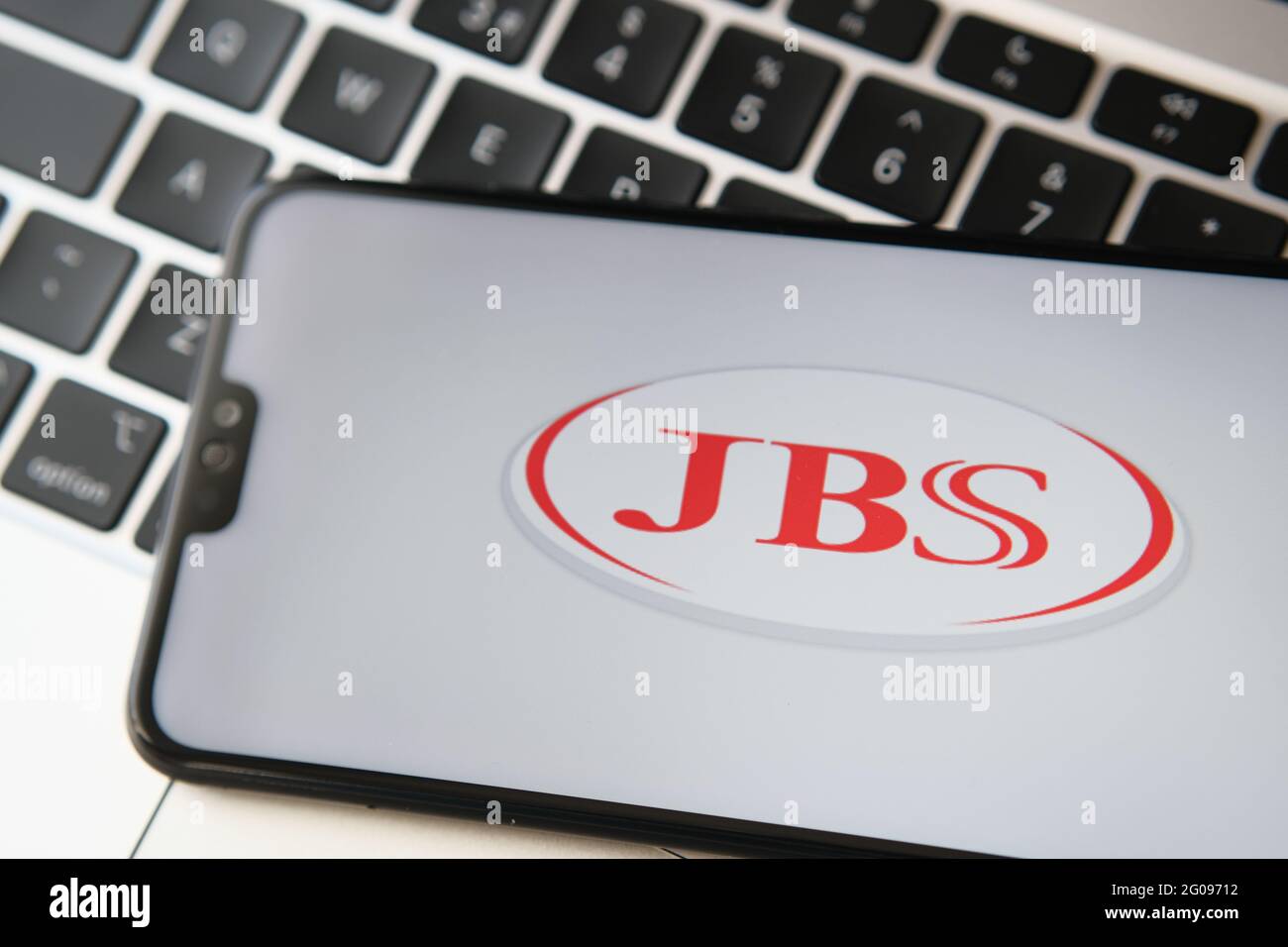 JBS meat producer logo seen on the smartphone screen with blurred money ...