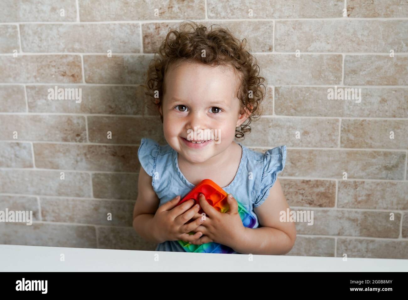 Child Playing Poppit Fidget Toy. Young Little Girl At Home Holding Pop ...