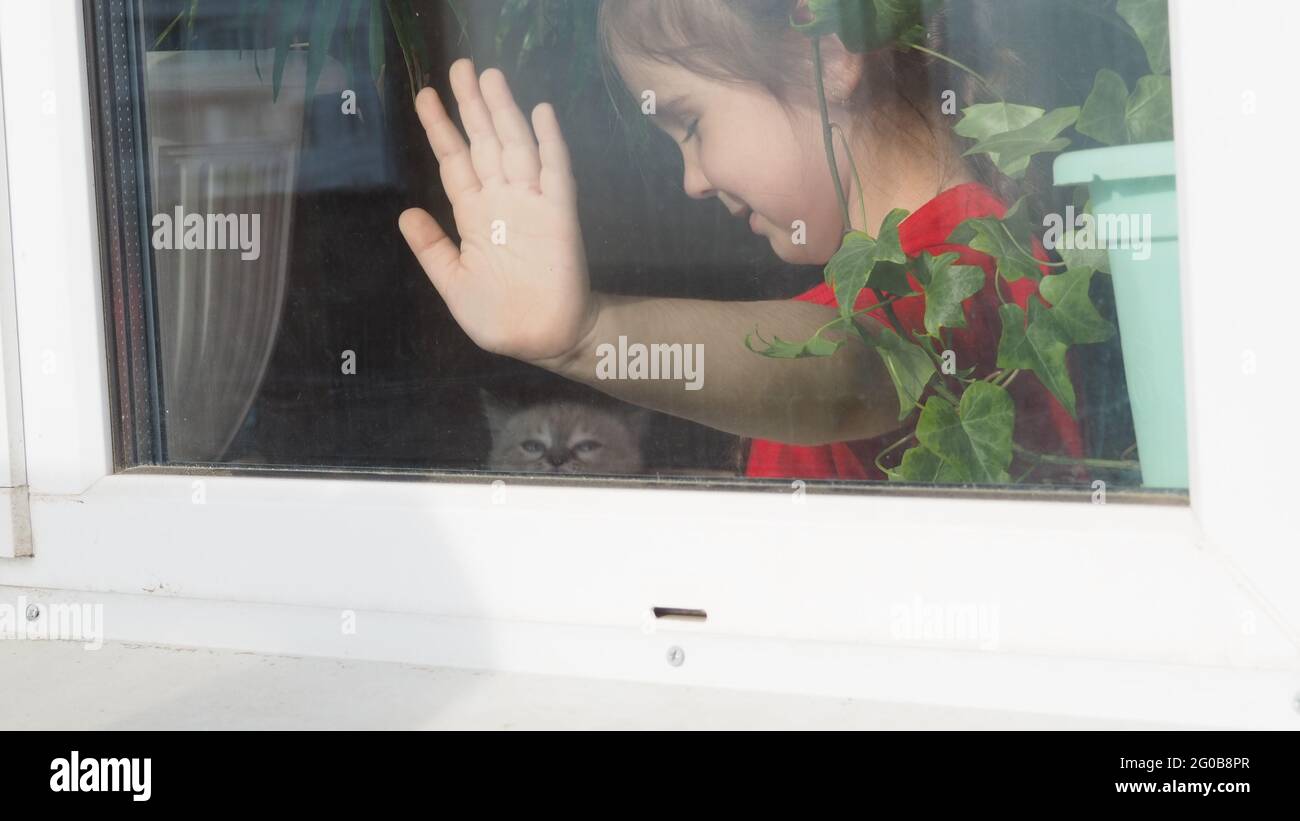 Beautiful little girl smiling and watching out the window. A child ...